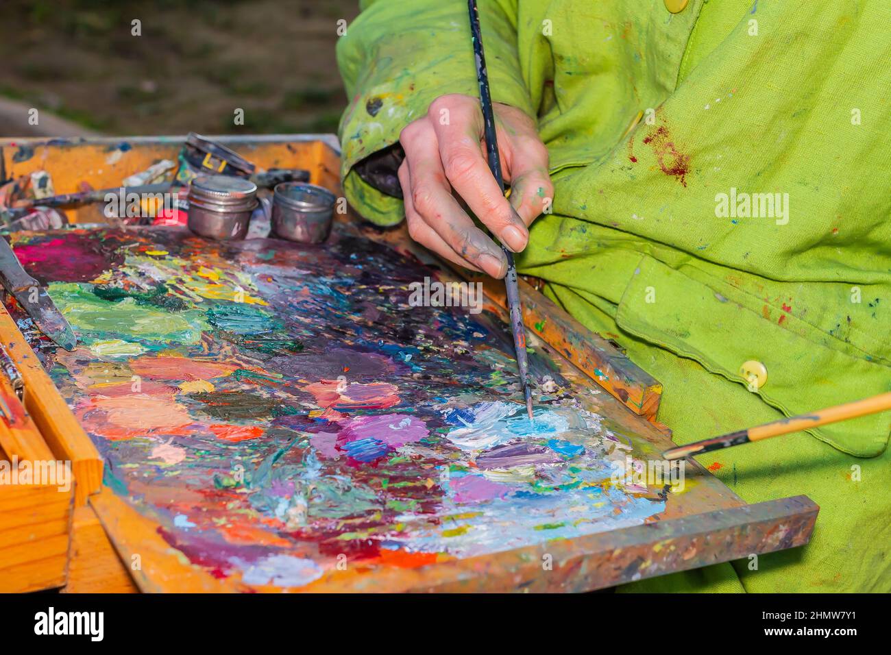 Closeup of an artist picking up a brush with paint on the color palette ...