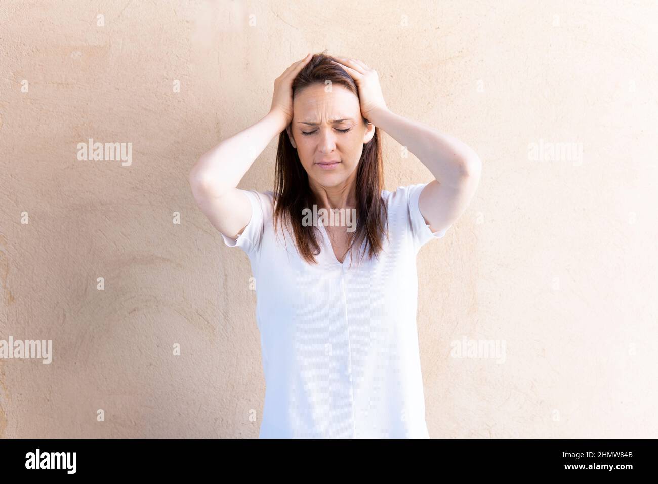 very stressed woman with hands on her head having a headache. concept ...