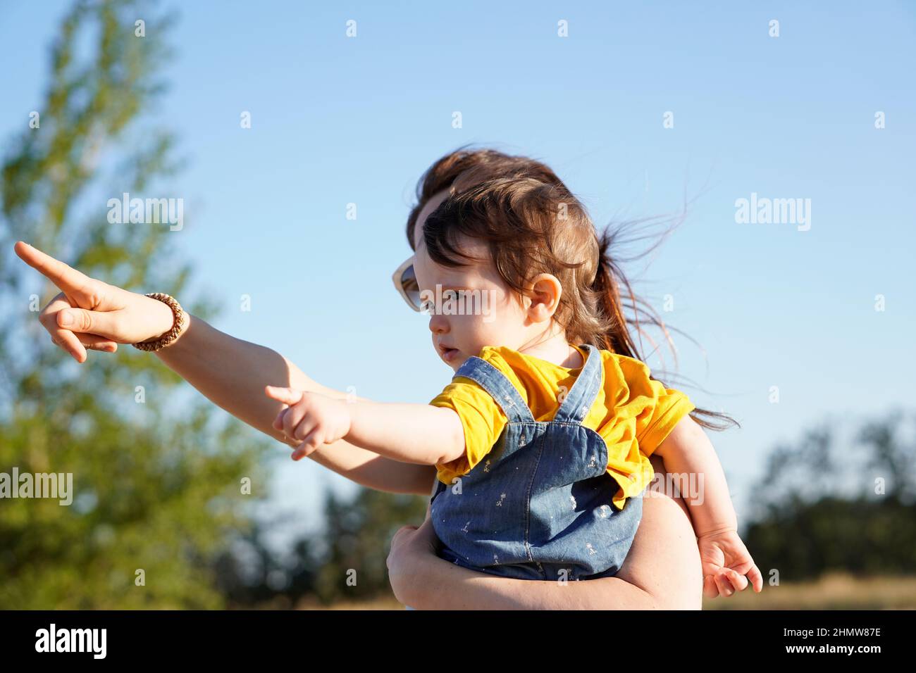 one year old boy pointed with his hand shown being held by his mother ...