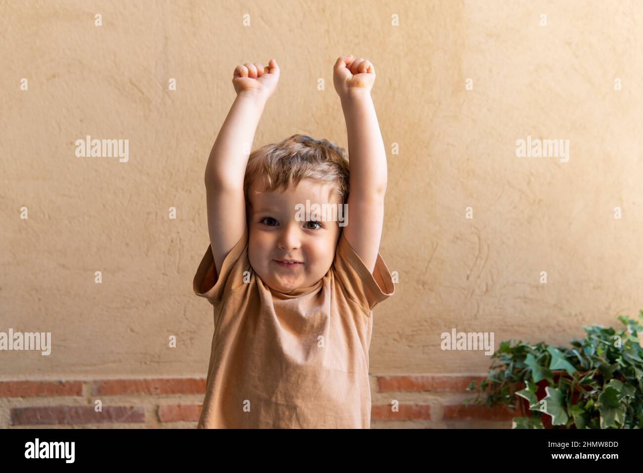 three year old boy raising his arms in victory symbol outdoors Stock ...