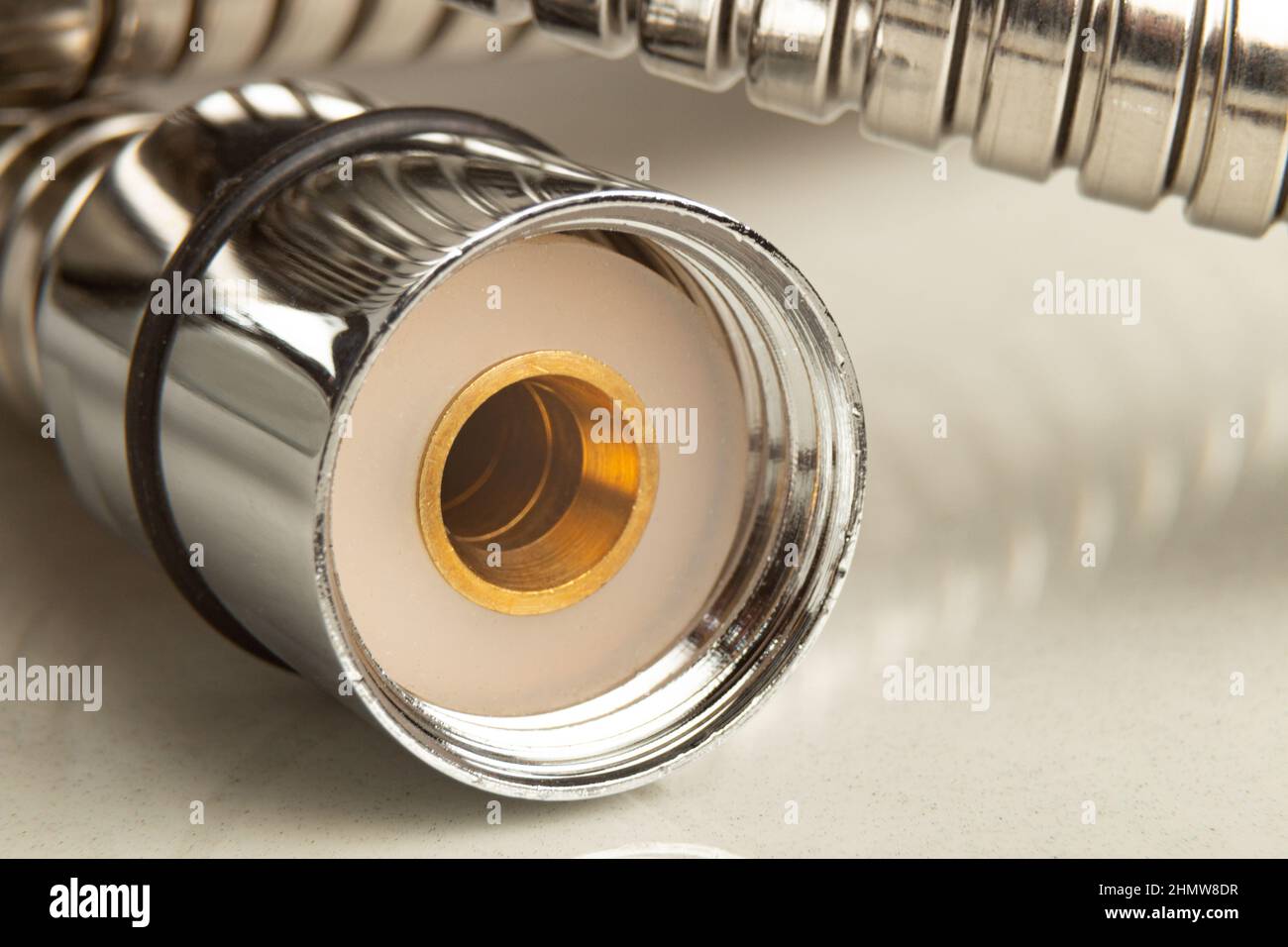 Fitting from a chrome-plated shower hose. Close-up side view on a white ...