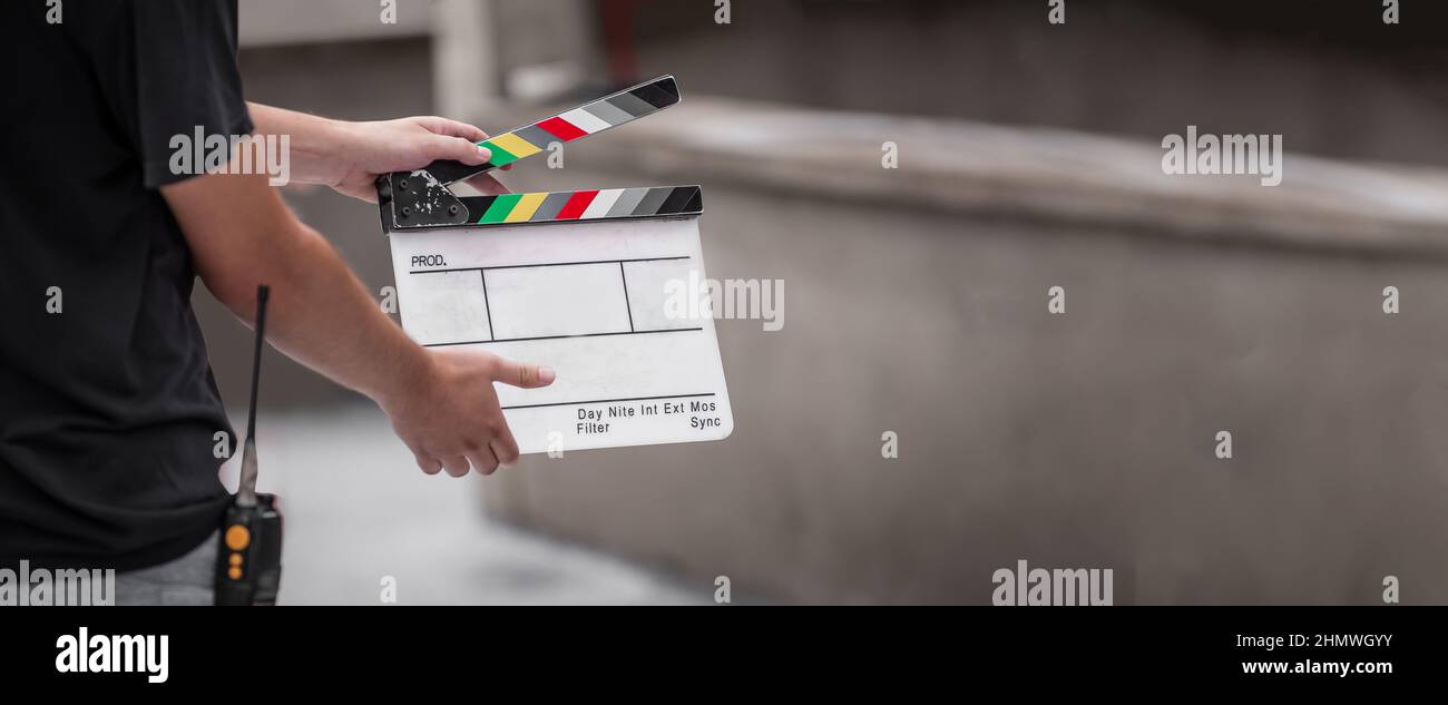 Filming on location. Man holding a clapperboard in front of the camera ...