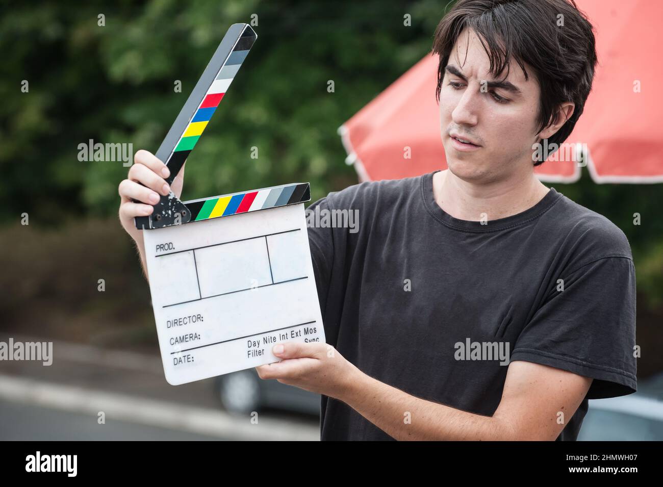 Filming on location. Man holding a clapperboard in front of the camera ...