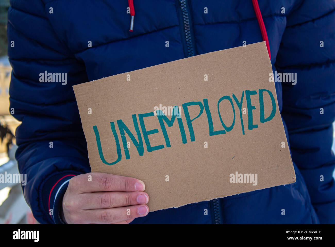 Man holding sign board with inscription UNEMPLOYED. Concept of losing ...
