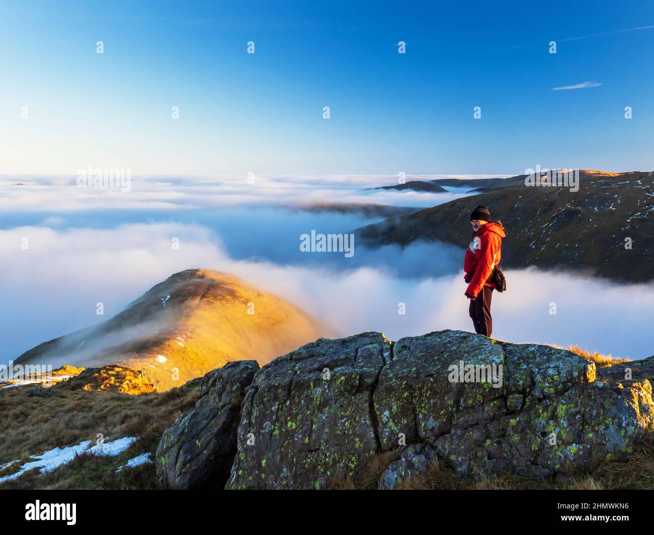 A mountaineer on Red Screes above valley mist from a temperature ...