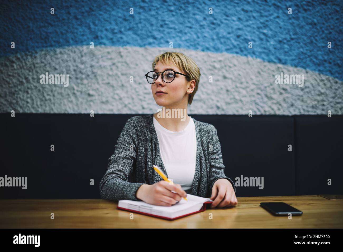 Pensive woman taking notes in notebook Stock Photo - Alamy