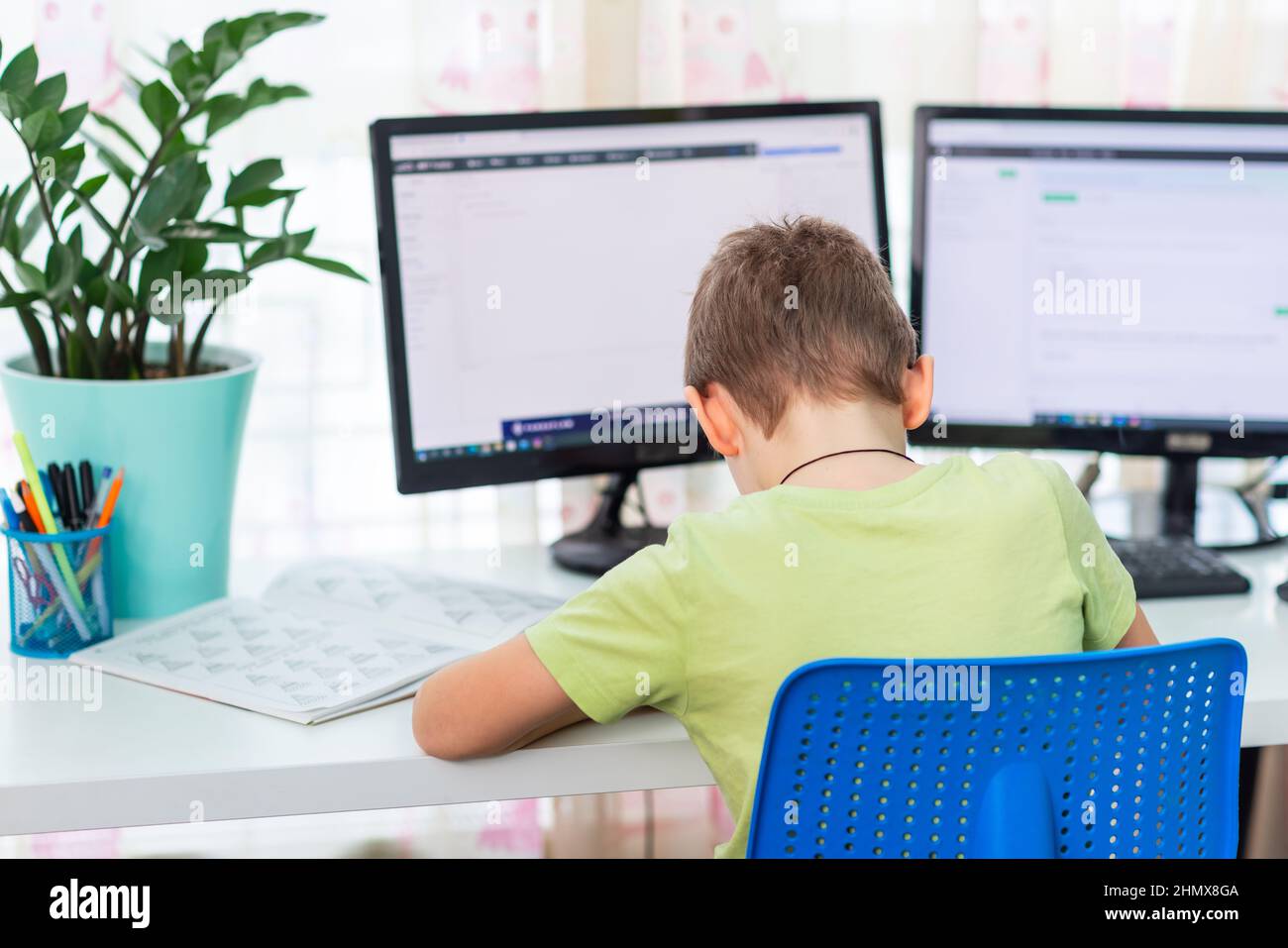 Little young school boy working at home with a laptop and class notes ...