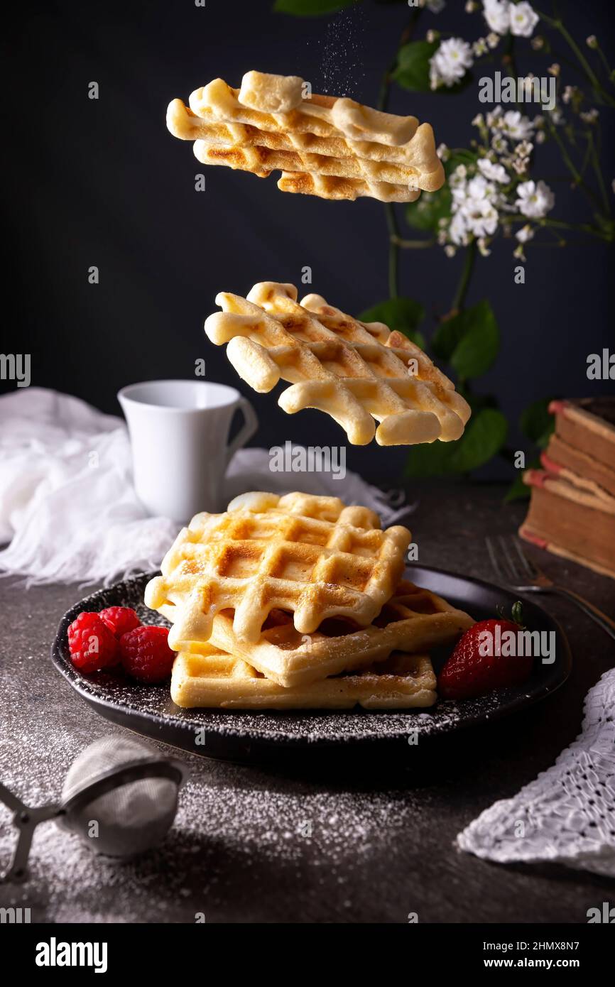 Homemade waffles floating with icing sugar and fruits Stock Photo - Alamy