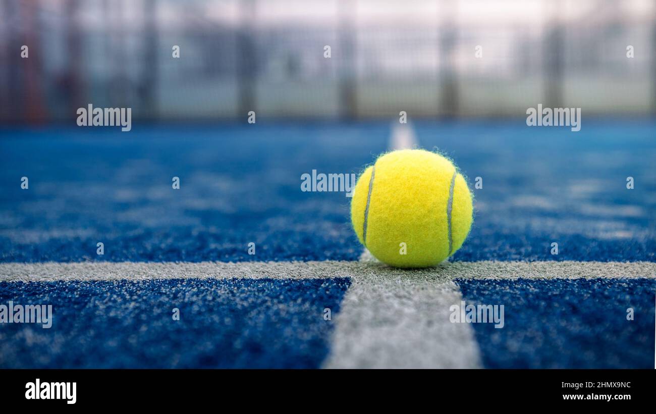 Yellow ball on floor behind paddle net in blue court outdoors. Padel ...