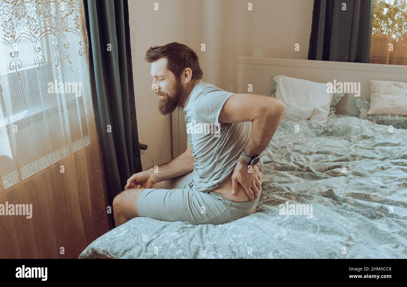 Caucasian man with back pain on the bed at home in the morning after ...