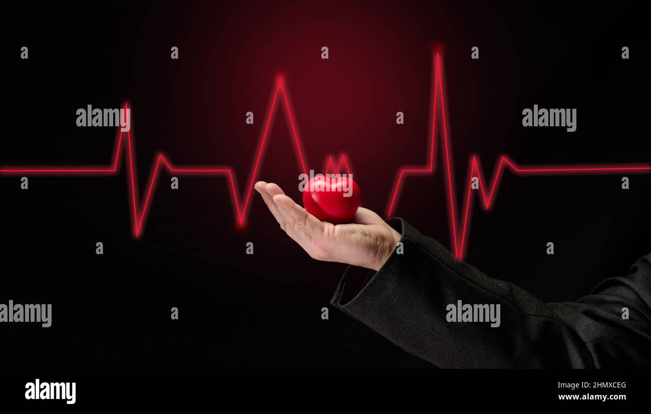 Male hand holding a red heart on a dark background, early diagnosis of ...