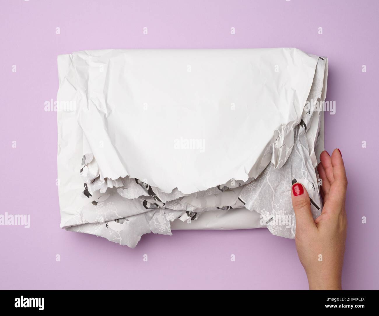 female hands hold crumpled white paper on purple background, top view ...