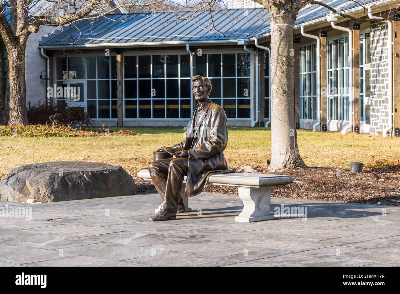 A bronze statue of President Abraham Lincoln seated on a bench in front ...