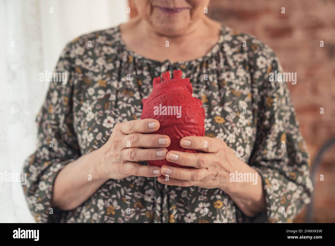 older person holding artificial heart reminding about health problems ...