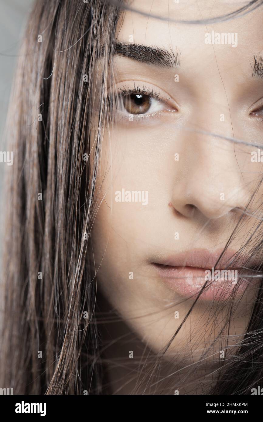 beauty fashion studio portrait of a beautiful young girl with windy hair in front of her face ...