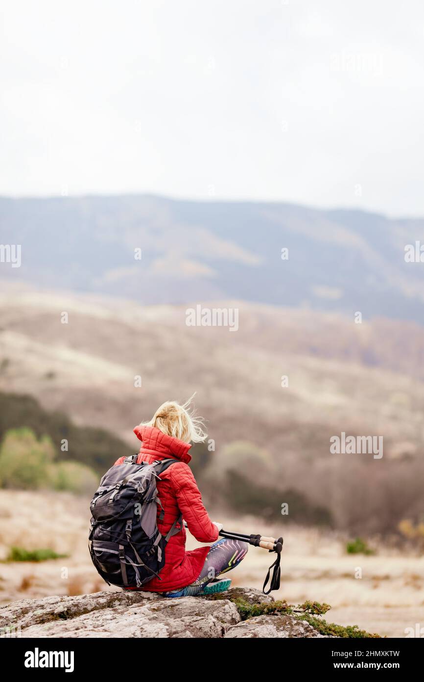 Hiker girl taking a rest on a rock in the mountains. Windy day. Travel ...