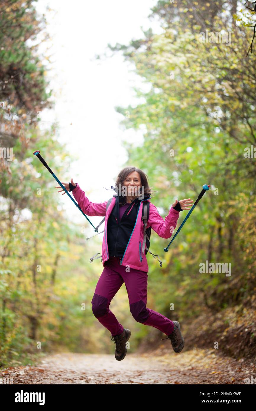 Hiker girl jumping on a trail in the mountains. Backpacker with hiking ...