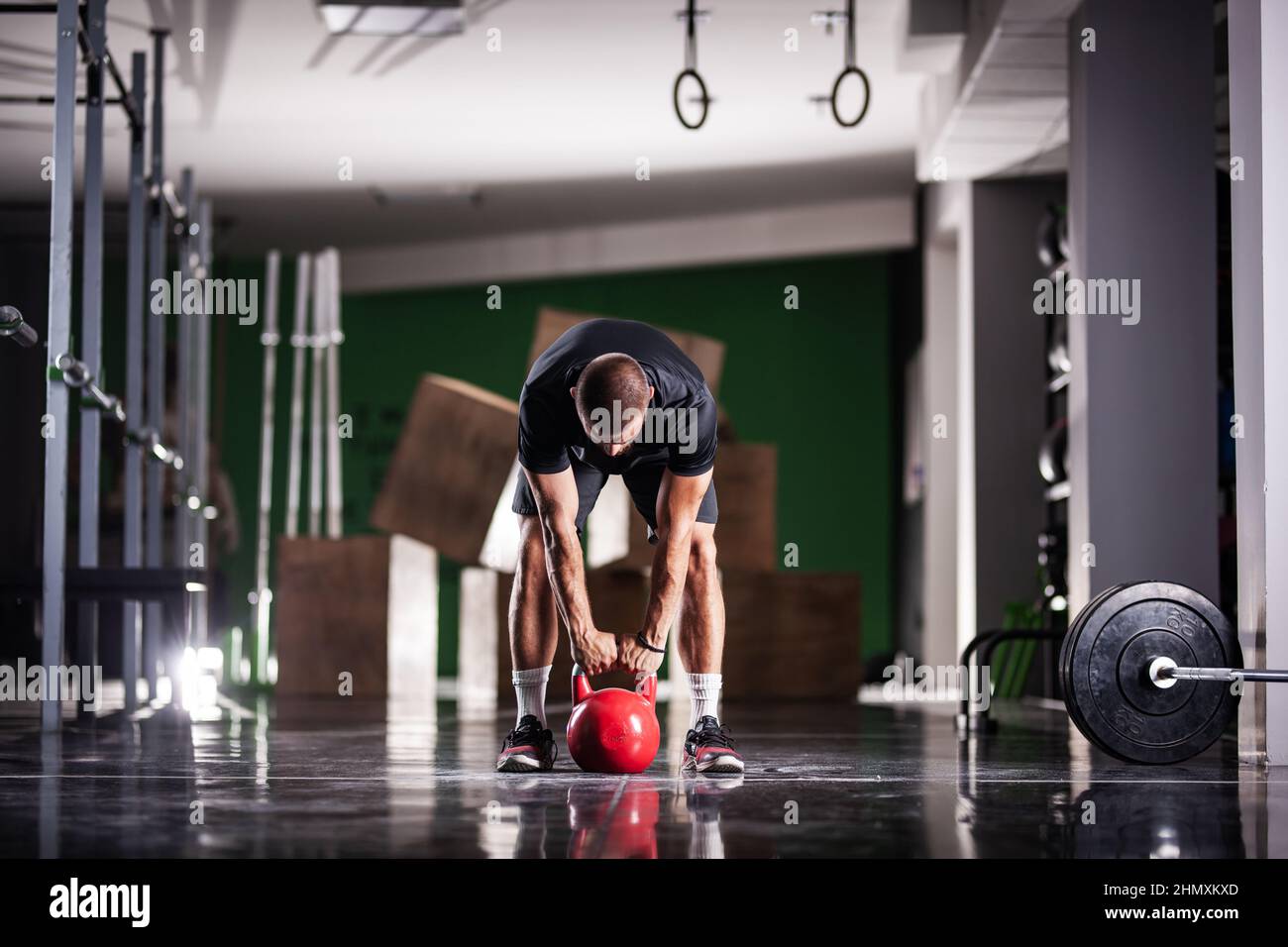 Muscular athlete power lifting a kettlebell. Man working out indoors ...