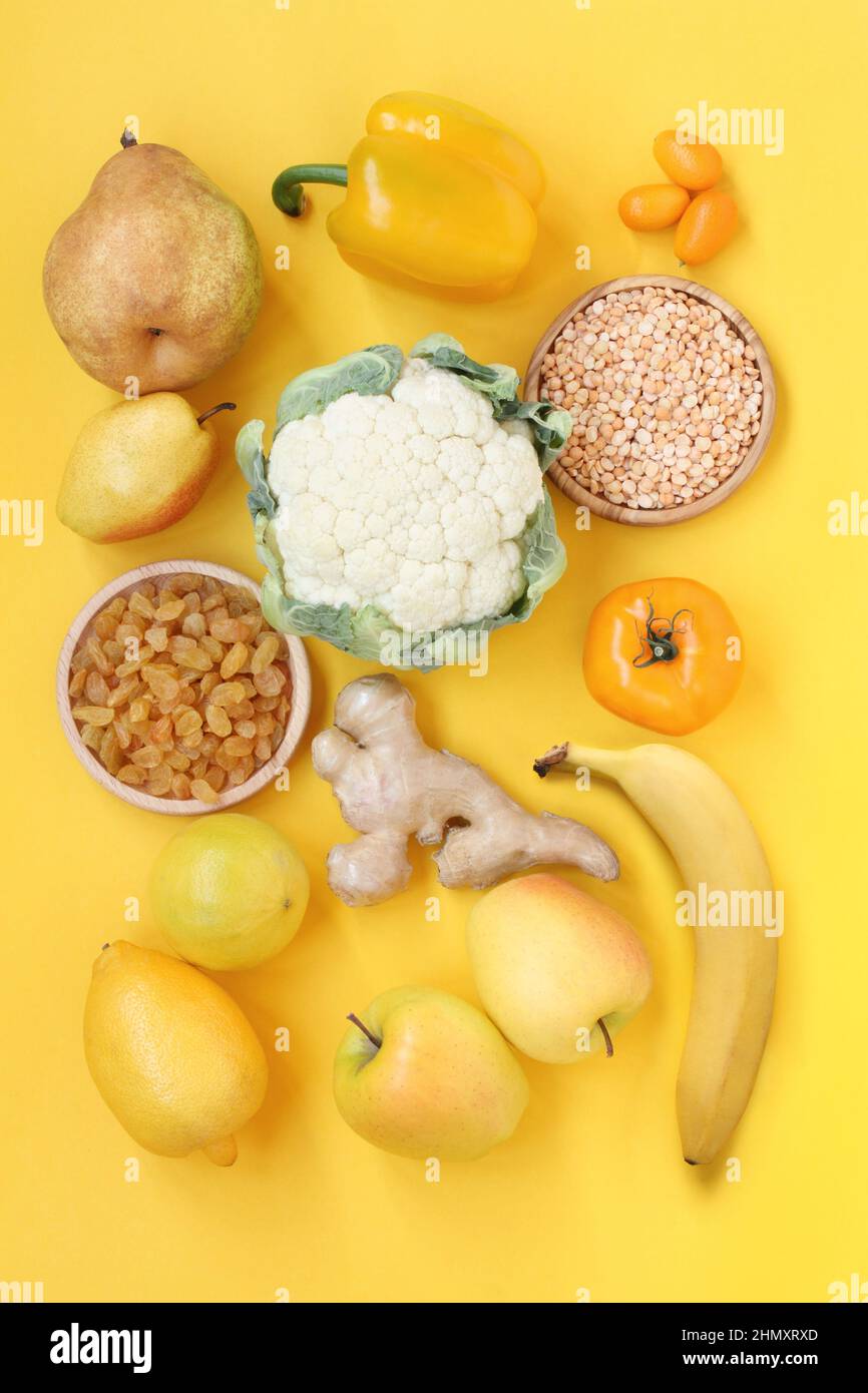 Yellow fruits and vegetables on a yellow background. Pears, raisins ...
