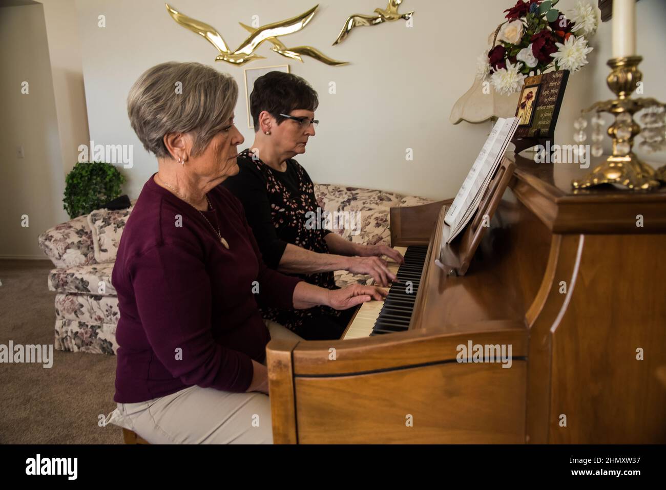 Two sisters sit down at the piano together to play a duet. it is both a ...