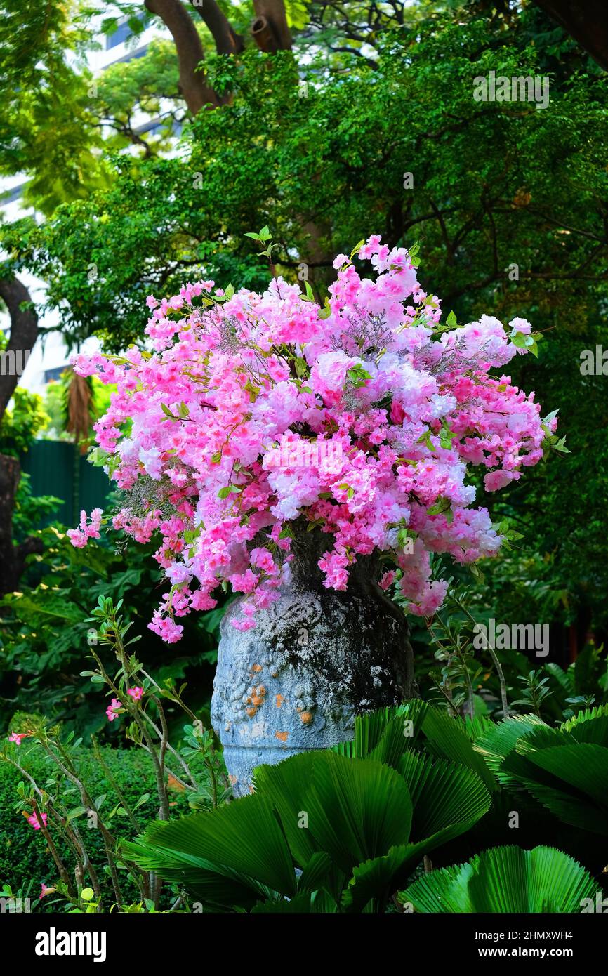 Magnificent pink roses in a big flower pot standing in romantic garden ...