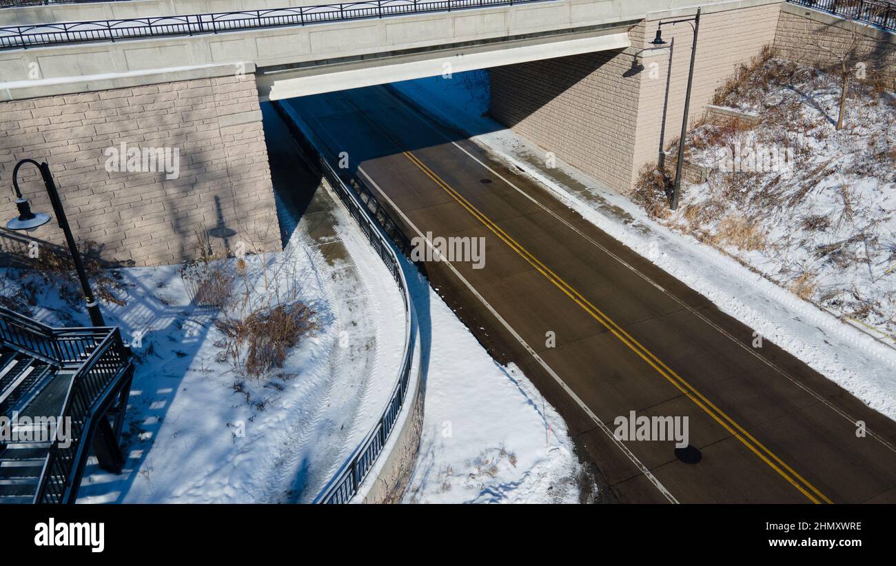 Snow covers the sidewalk and ice covered street. Stair case to top of ...
