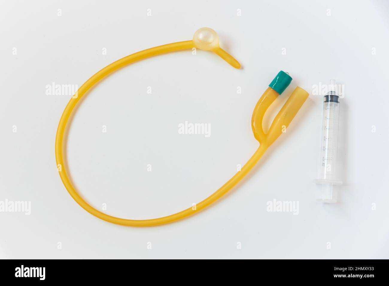 Urinary foley catheter with inflated balloon and syringe on white ...