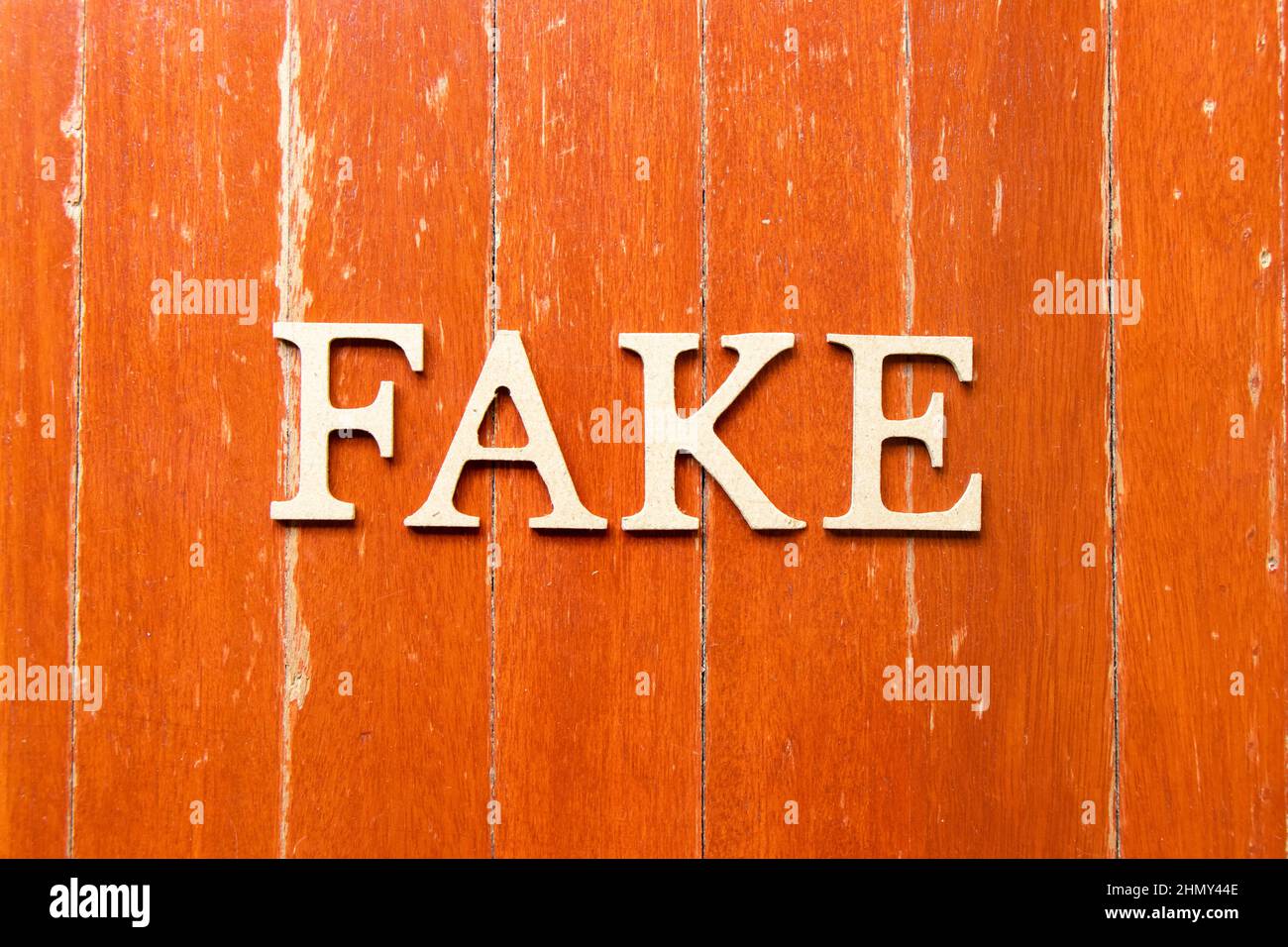 Alphabet letter in word fake on old red color wood plate background ...