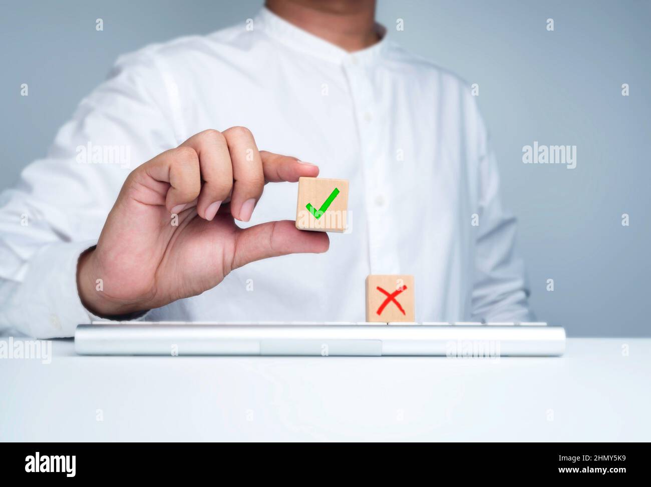 Green check mark icon, on wooden cube block in businessman's hand and ...