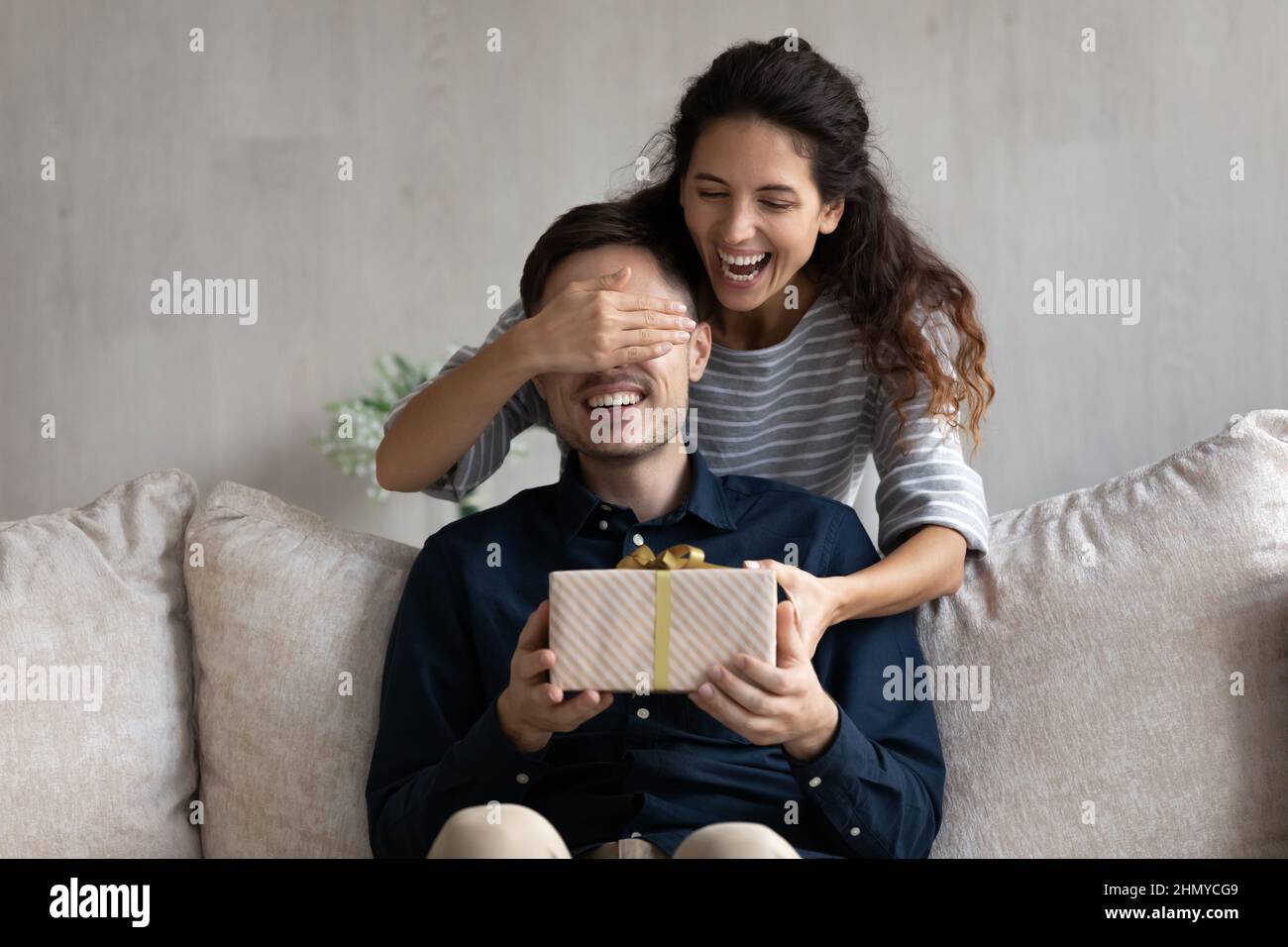 Excited young Latin woman giving surprise gift to excited boyfriend ...
