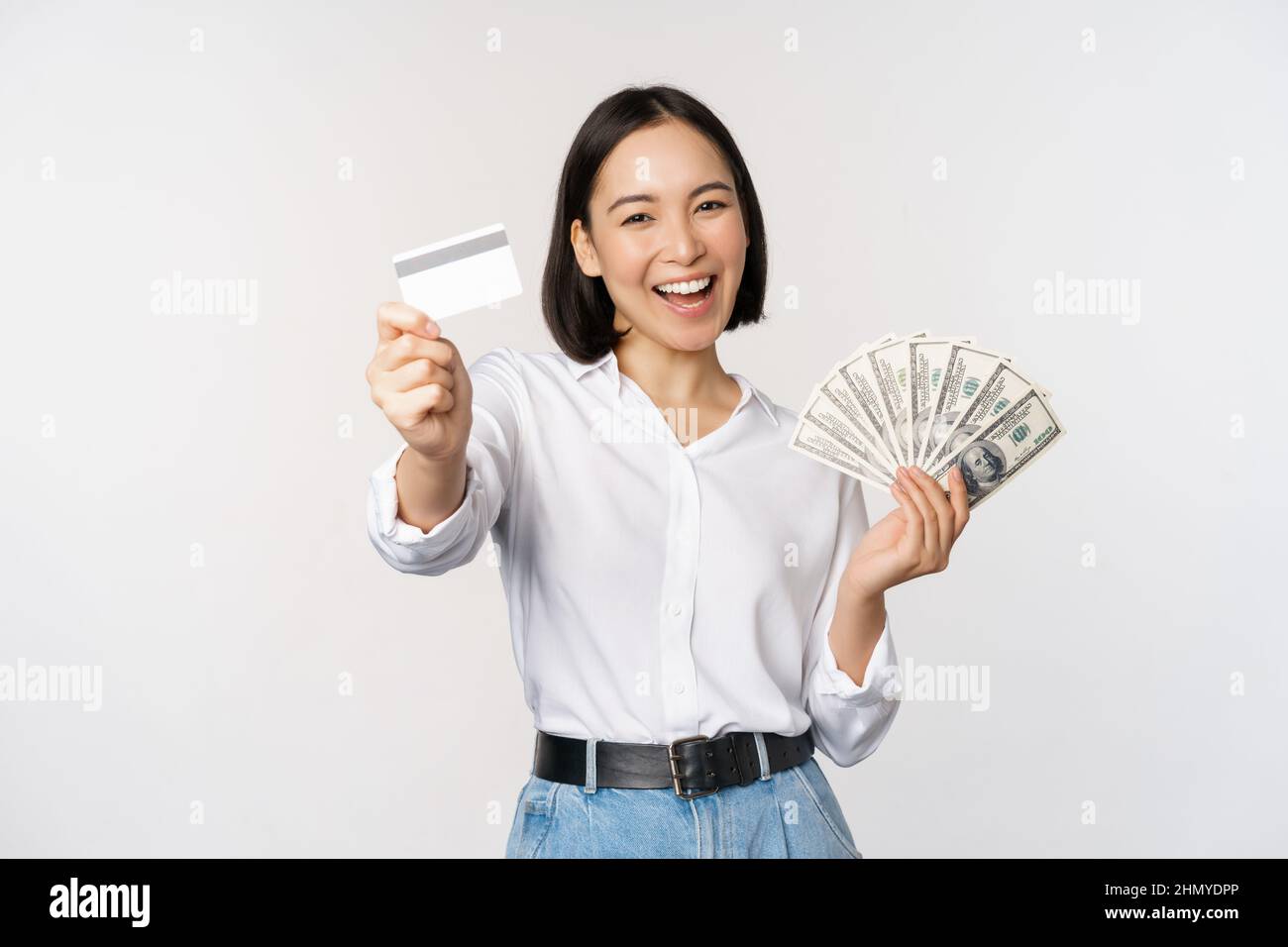 Happy korean woman holding credit card and money dollars, smiling and ...