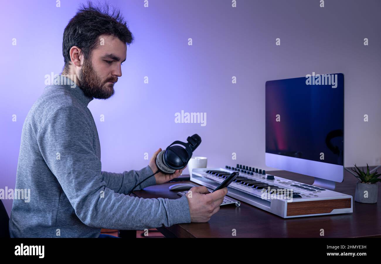Male musician creates music using computer and keyboard, musician ...