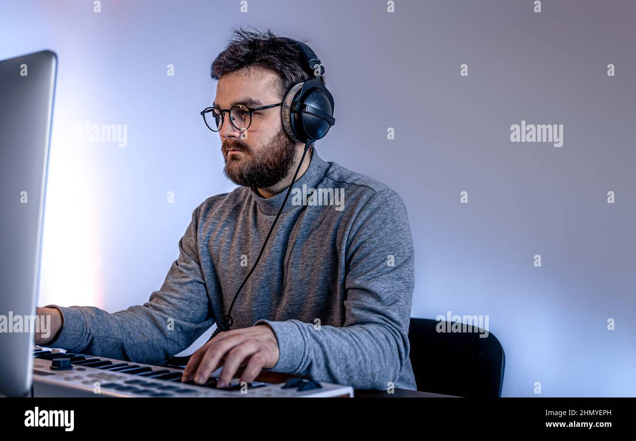 Male musician creates music using computer and keyboard, musician ...
