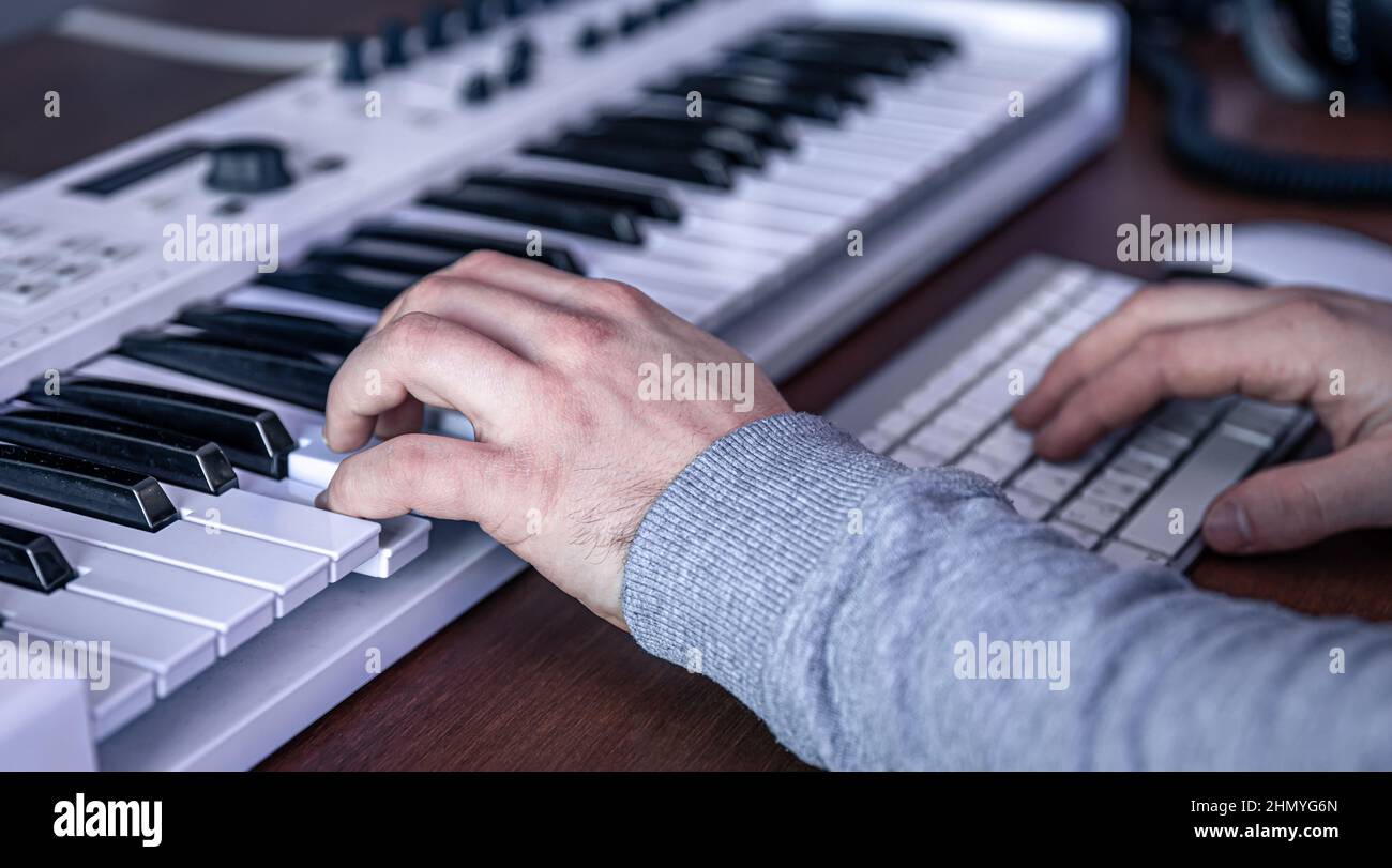 Male musician creates music using computer and keyboard, musician ...