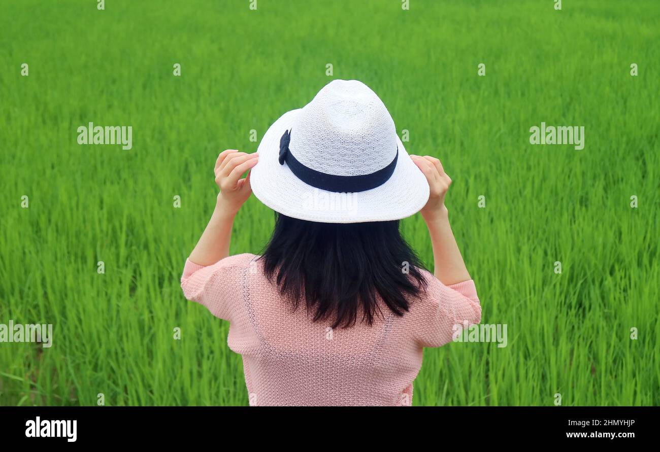 Woman in white hat relaxing in vibrant green paddy field Stock Photo ...