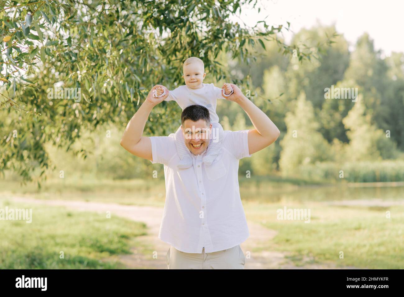 A young happy father of a large size holds his little son around his ...