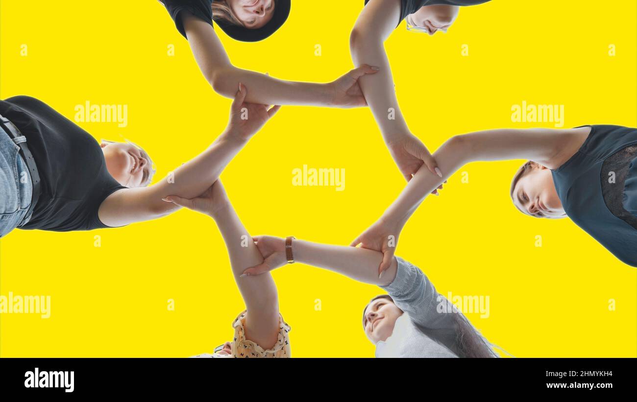 Friends join their wrist and make a circle on a yellow background ...