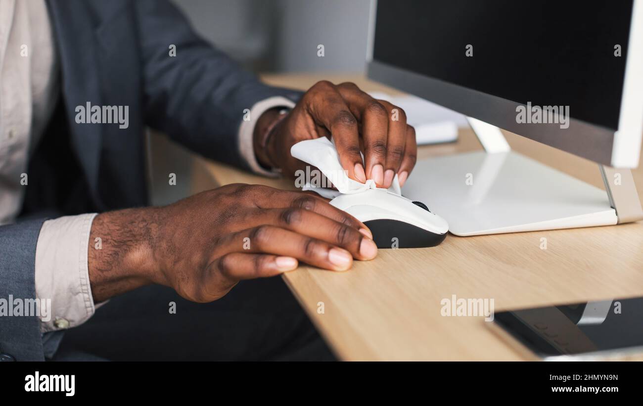 Unrecognizable black office worker wiping computer mouse with ...
