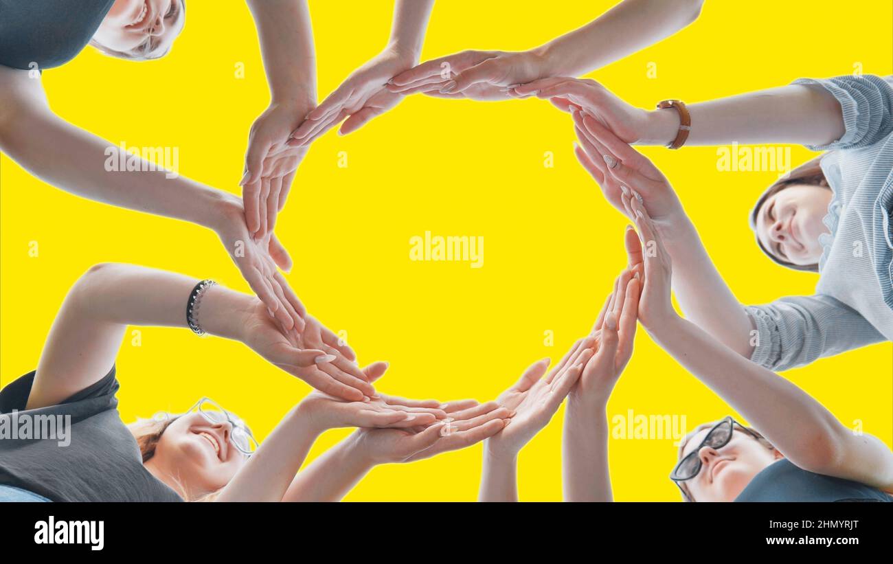 Friends make a circle with their palms against a yellow background ...