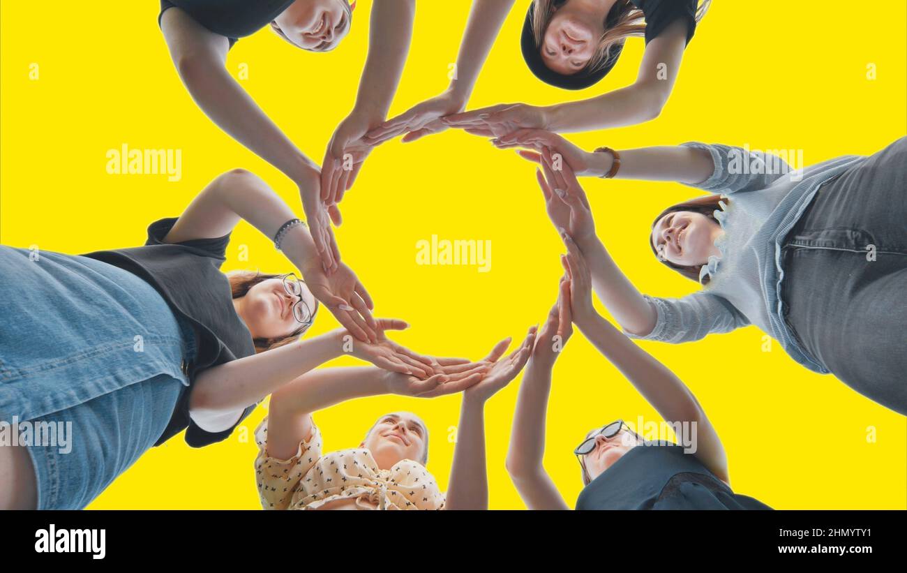 Friends make a circle with their palms against a yellow background ...