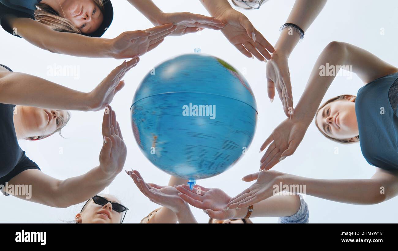Schoolgirls hug the earth globe with their hands, making a circle out ...