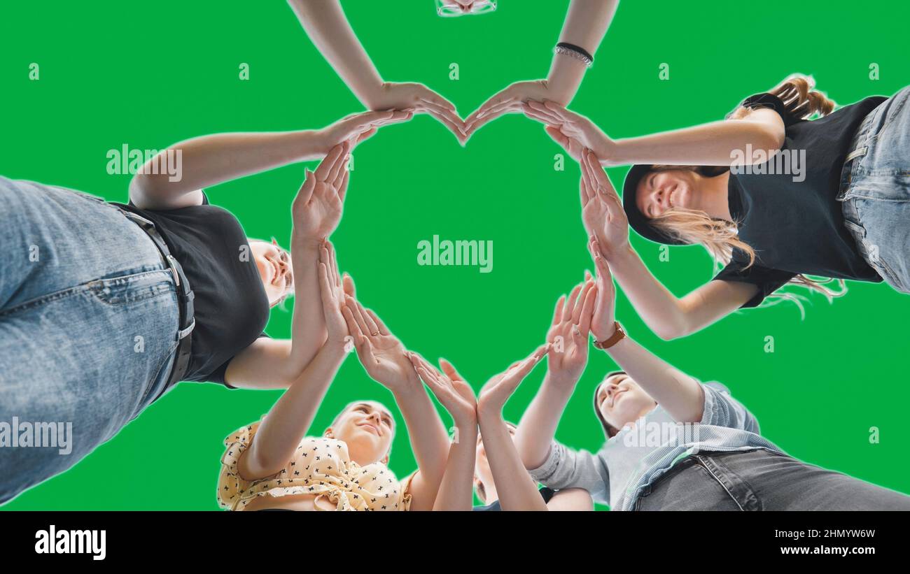 Girlfriends girls make a heart shape from their hands on a green ...