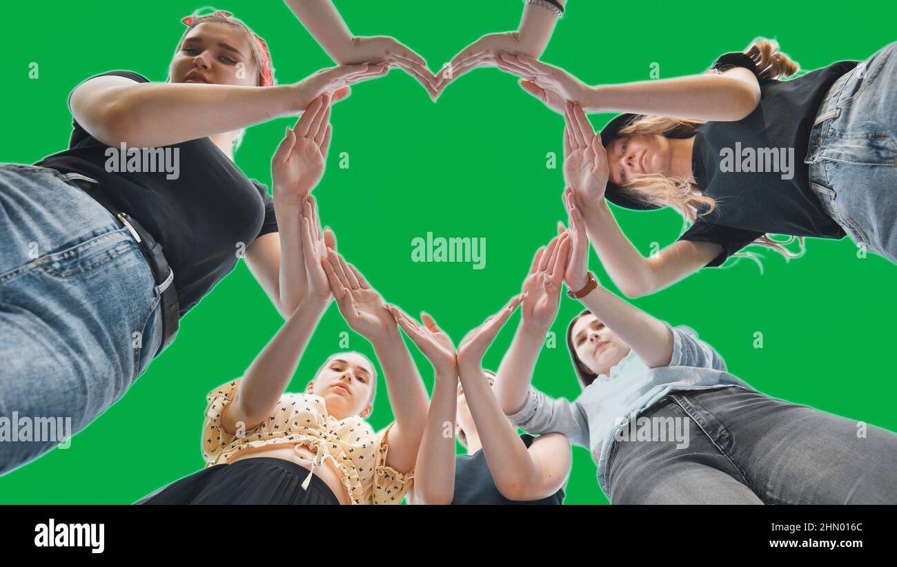 Girlfriends girls make a heart shape from their hands on a green ...