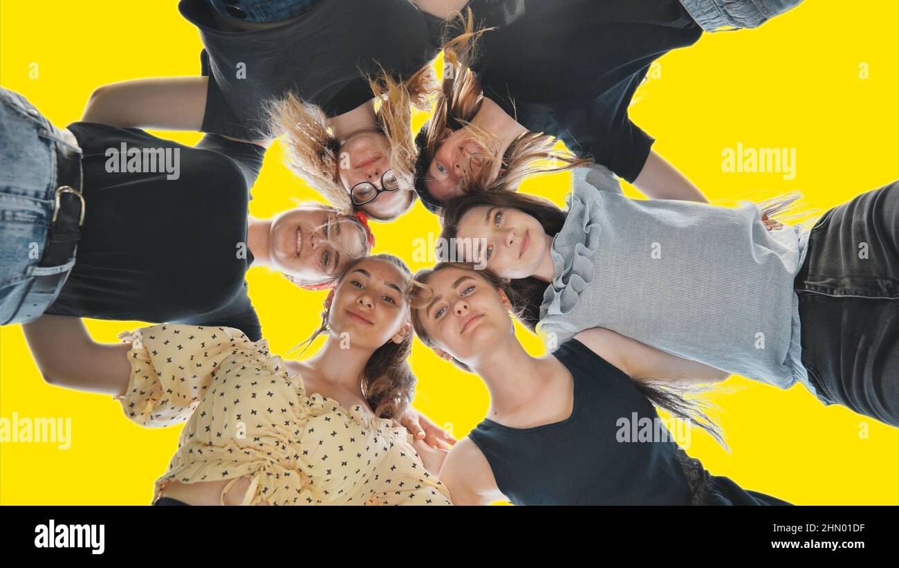 Happy girls friends hugging in a circle on a yellow background Stock ...