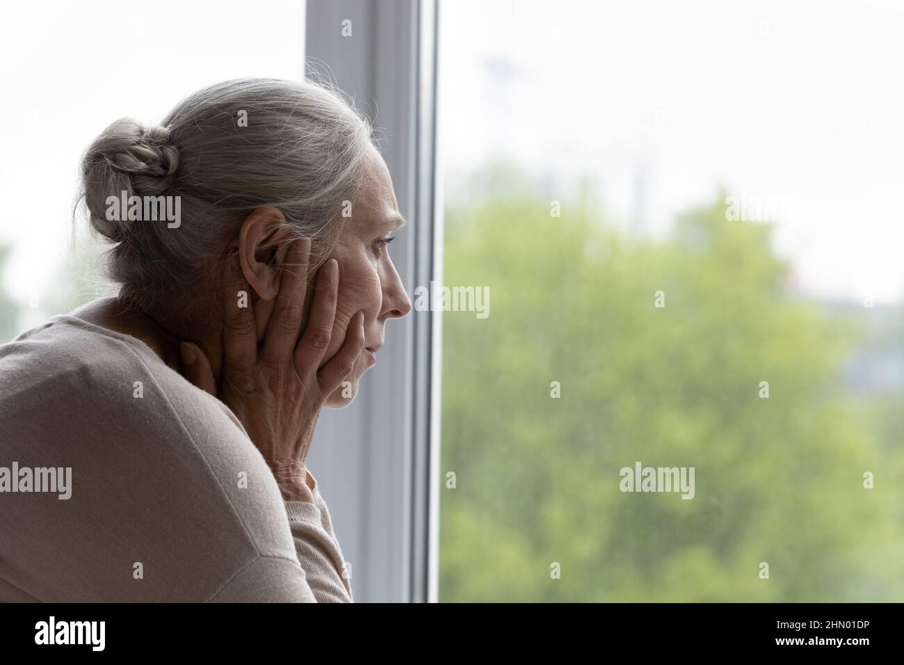Older woman looking out window hi-res stock photography and images - Alamy