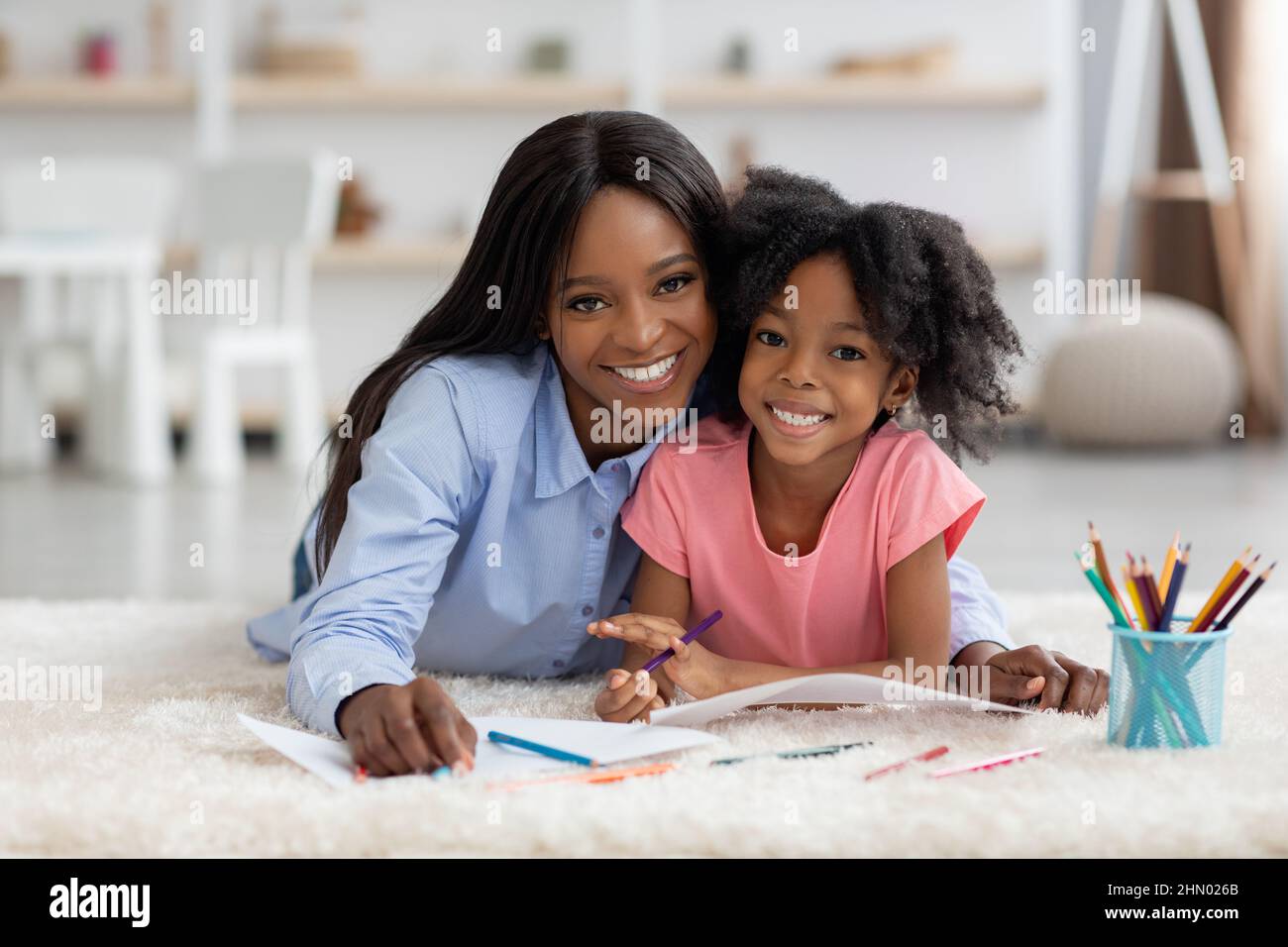 Portrait of cheerful loving mom and little girl coloring together Stock ...
