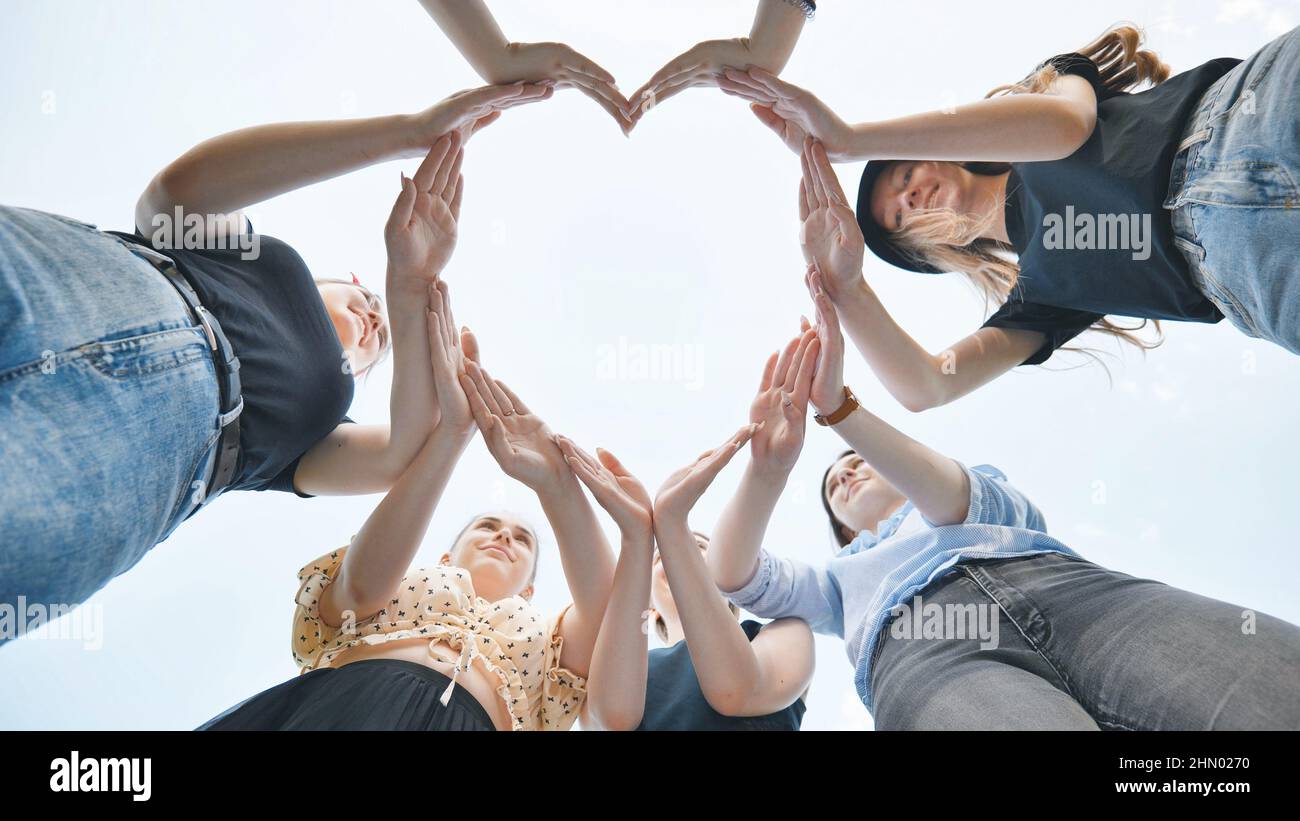 Girlfriends girls make a heart shape from their hands against the blue ...