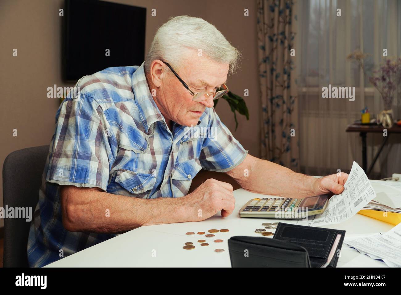Upset Senior man sitting at the table and calculating finances. Old man ...
