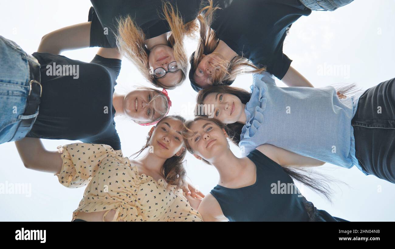 Happy girls girlfriends hugging in a circle on a background of blue sky ...
