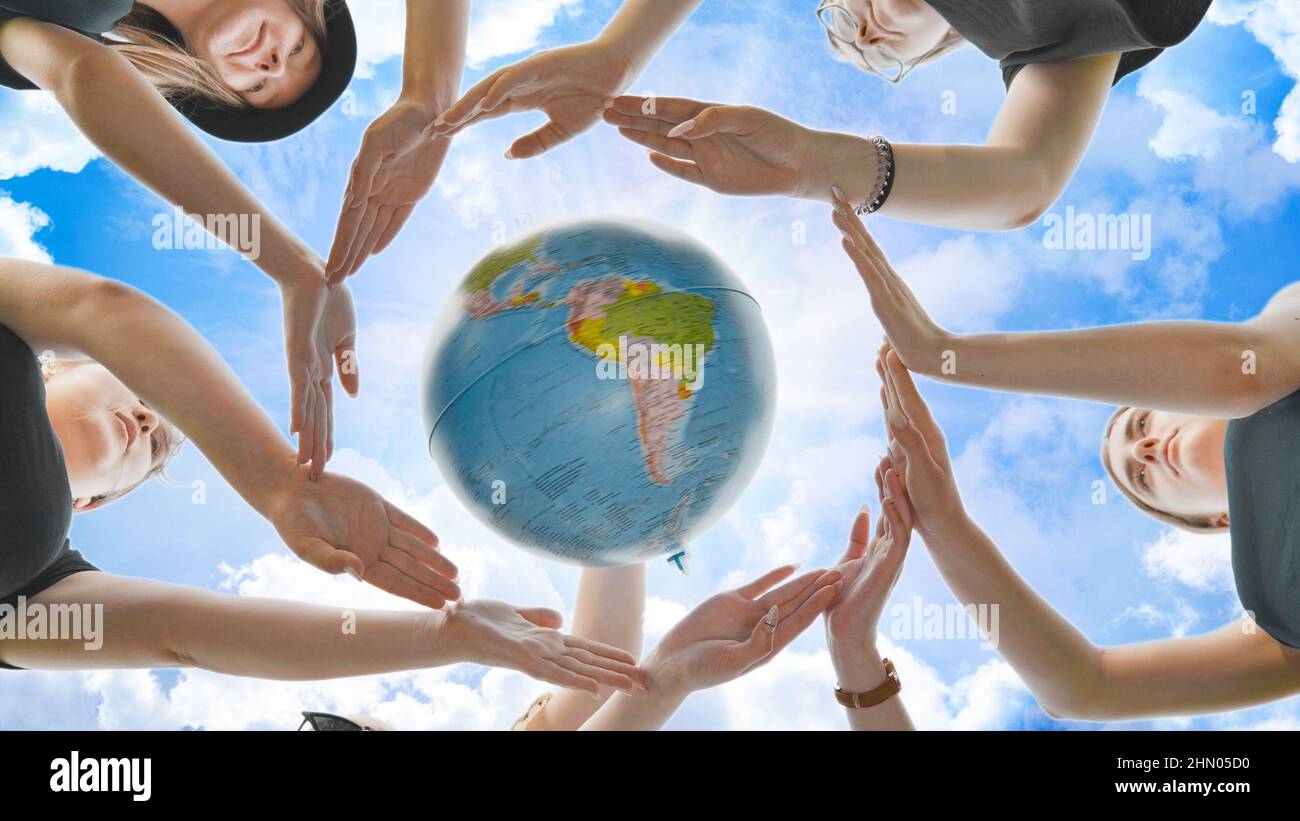 Schoolgirls hug the earth globe with their hands, making a circle out ...